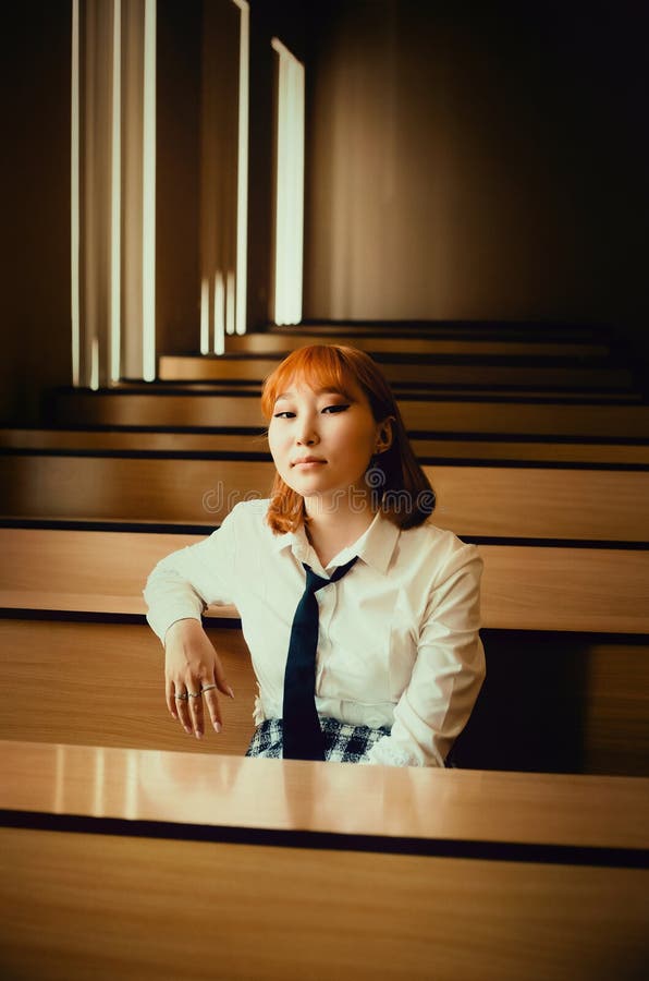 An Asian Ginger Female Student, Dressed in Uniform, Sitting on a ...