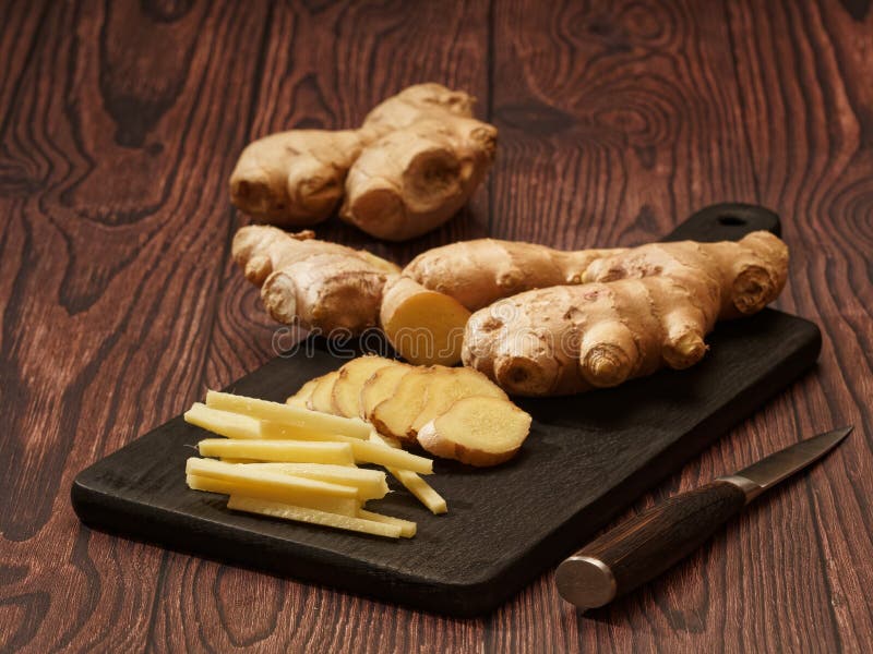 Ginger Root Cut into Strips and Slices on a Burned Wood Cutting Board ...