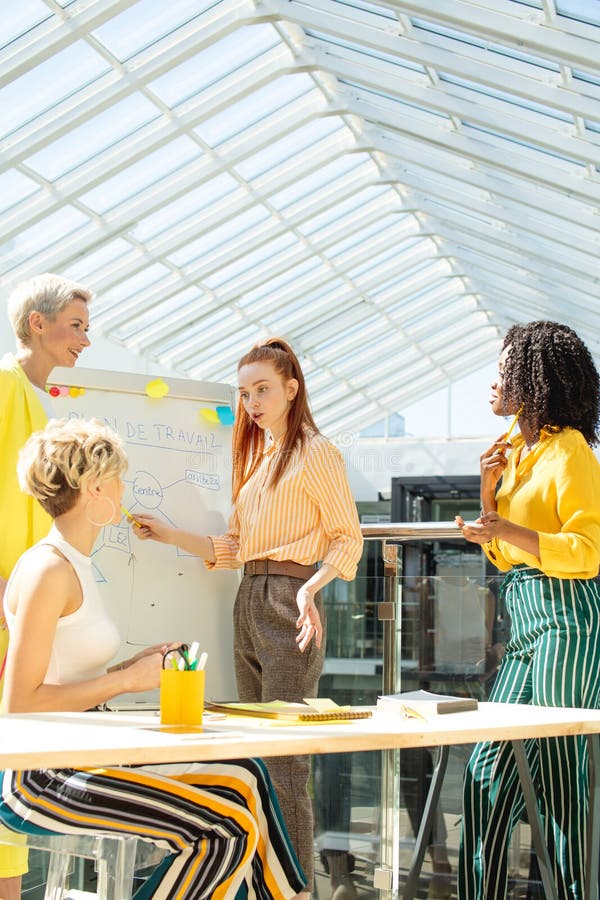 Ginger Team Leader Standing in Front of the Flipchart, Pointing To it ...