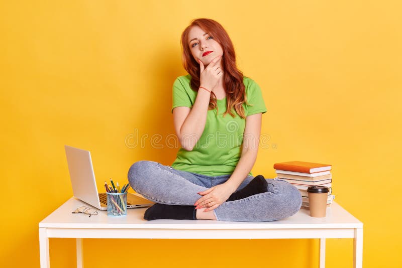 Ginger Thoughtful Female Student Studying while Sitting on White Desk ...