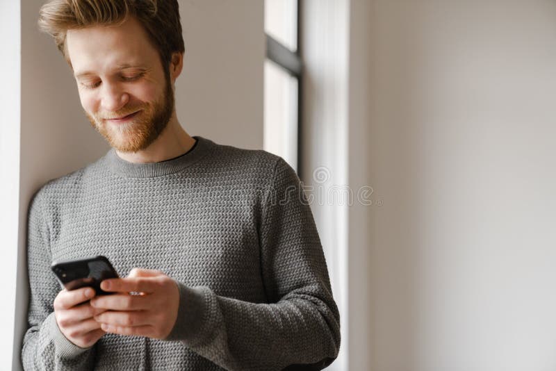 Ginger Young Man Using Mobile Phone while Leaning on Wall Stock Photo ...