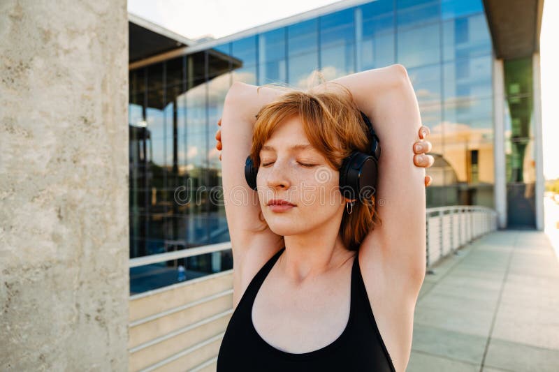 Ginger Young Woman in Headphones Doing Exercise during Workout Stock ...