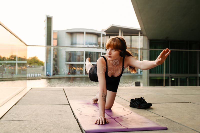 Ginger Young Woman in Headphones Doing Exercise during Workout Outdoors ...