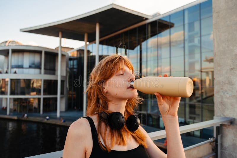 Ginger Young Woman with Headphones Drinking Water after Workout Stock ...