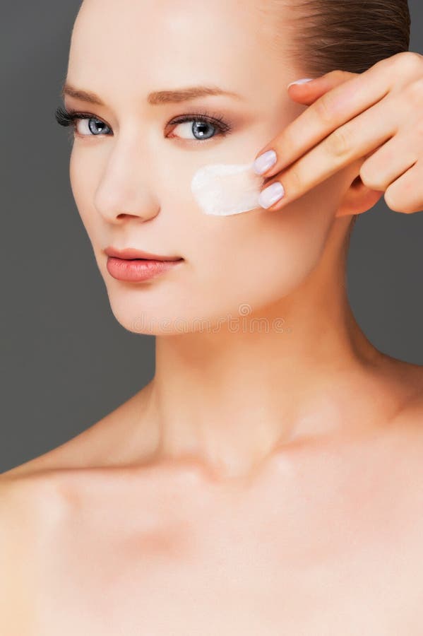 Girl Applies Moisturizing Cream On Her Face With Manicured Hands