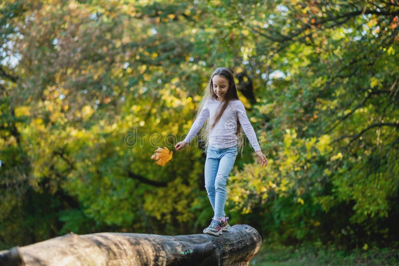 A Girl Balances on a Fallen Log with a Leaf in Her Hand Stock Image ...