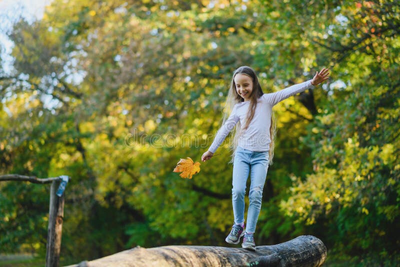 A Girl Balances on a Fallen Log with a Leaf in Her Hand Stock Image ...