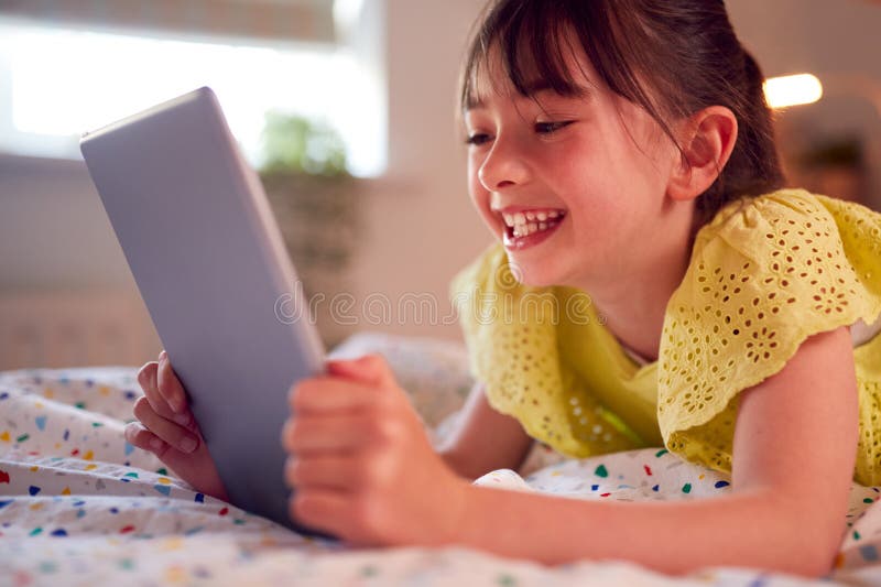Girl in Bedroom Lying on Bed Enjoying Using Digital Tablet Stock Photo ...