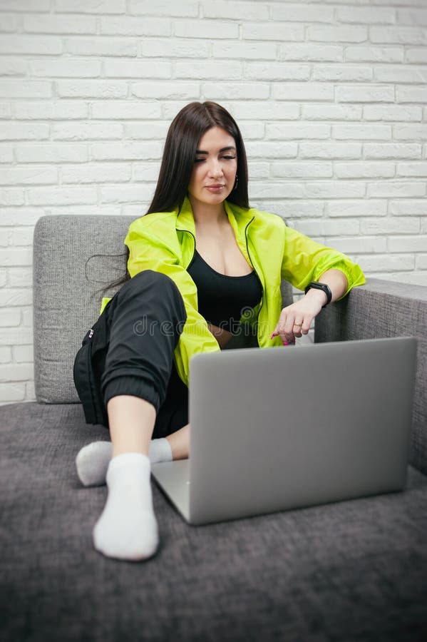 A Girl in a Bright Tracksuit with a Laptop on the Couch Stock Image ...