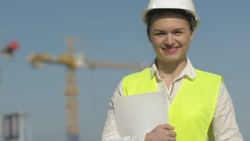 Girl Builder in Protective Clothes at Construction Site. Girl Holds a ...