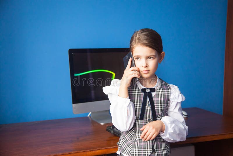 Girl in a Business Suit Stands at the Computer and Talks on the Phone ...