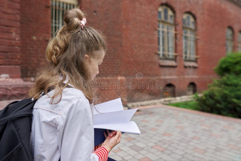Girl Child with Backpack Sitting in School Yard Reading Notebook, Copy ...