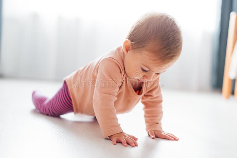 A Girl Child Learns To Crawl on the Floor. First Steps Stock Photo ...