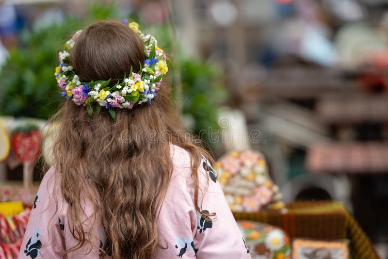 A Girl with a Crown of Flowers Looks Forward. View from the Back ...