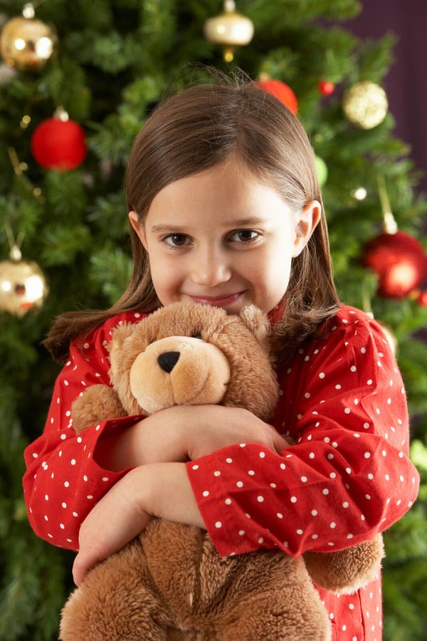 Girl Cuddling Teddy in Front of Christmas Tree Stock Image - Image of ...