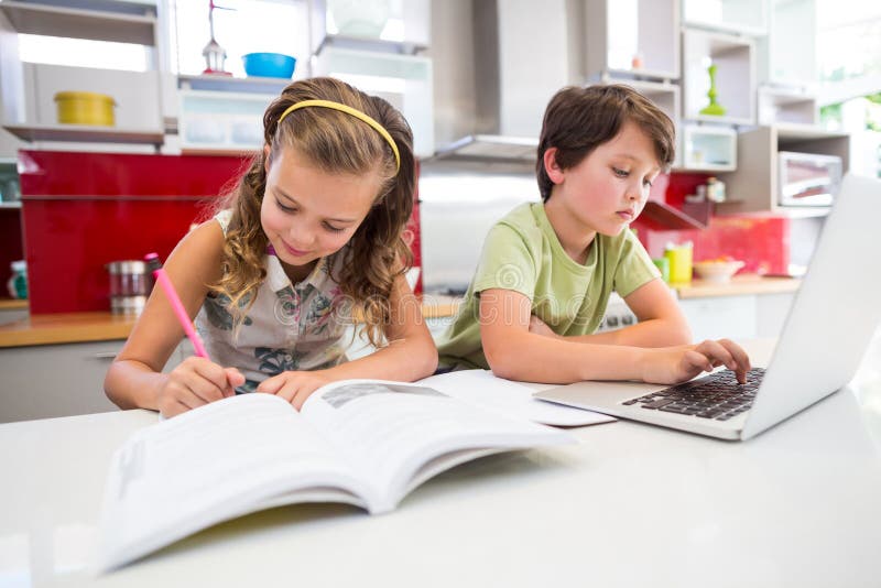 Girl Doing Her Homework while Boy Using Laptop in Kitchen Stock Image ...