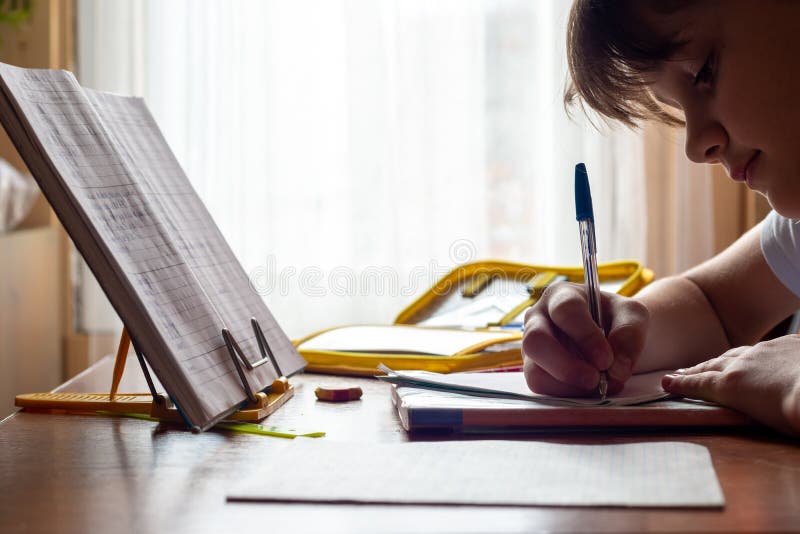 Girl Doing Homework while Sitting at a Table Near the Window in Natural ...
