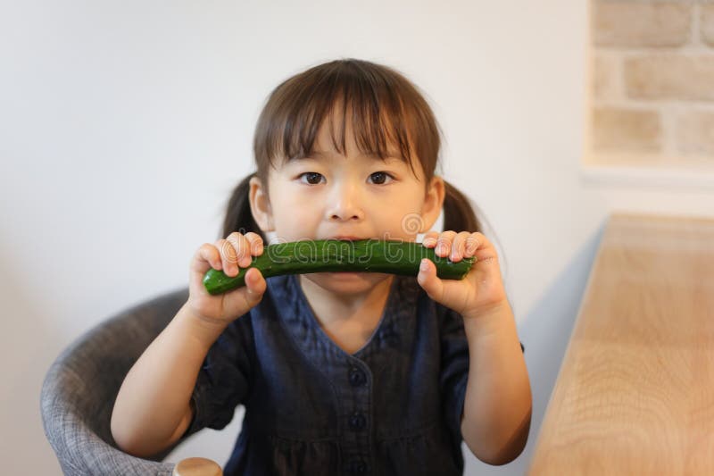 Girl eating cucumber stock photo. Image of education - 344466444