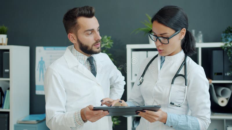 Girl and Guy in Medical Uniform Using Tablet Computer Talking in Clinic ...