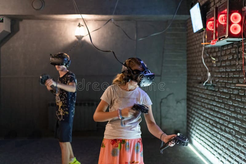 A Girl and a Guy in Virtual Reality Helmets with Joysticks Play ...