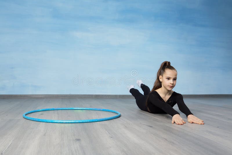 A Girl Gymnast In A Black Gymnastic Swimsuit Is Sitting On A Cross