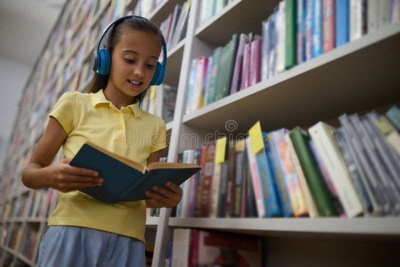 Girl in Headphones Reading a Book in the Library Stock Image - Image of ...