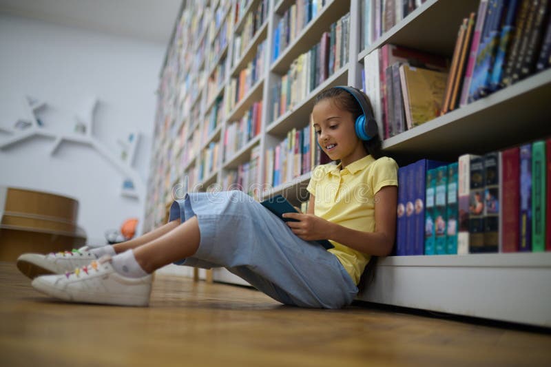 Girl in Headphones Reading a Book in the Library Stock Photo - Image of ...