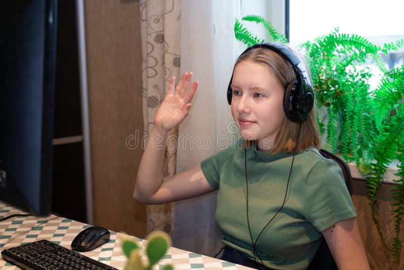 Girl in Headset Sitting Near Window and Waves To Screen of Computer ...
