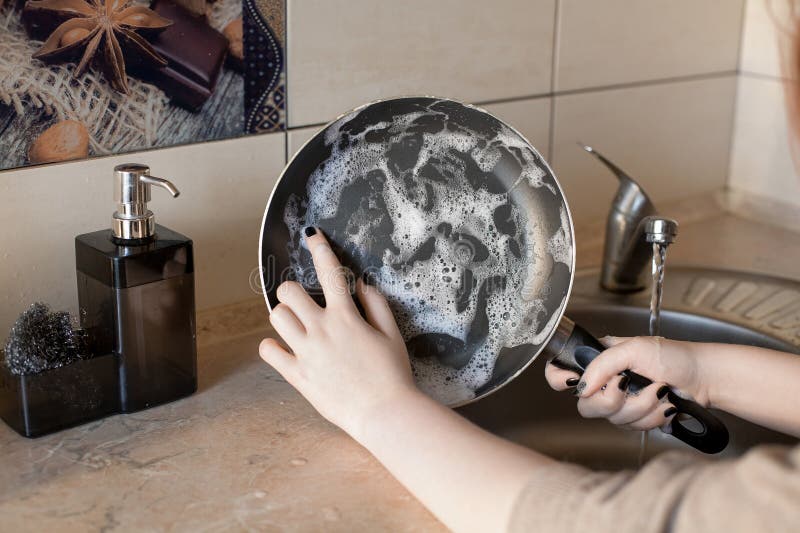 The Girl Holds in Her Hands a Large Frying Pan in Soap, in the Sink in ...