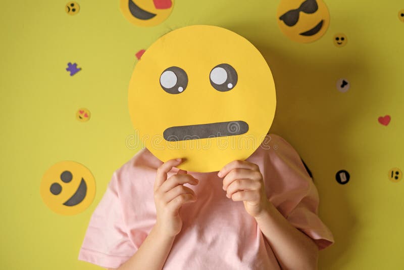 The Girl Holds a Sad Yellow Tearful Smile Face in Her Hands, Hiding Her ... The Girl Holds a Sad Yellow Tearful Smile Face in Her Hands, Hiding Her ...