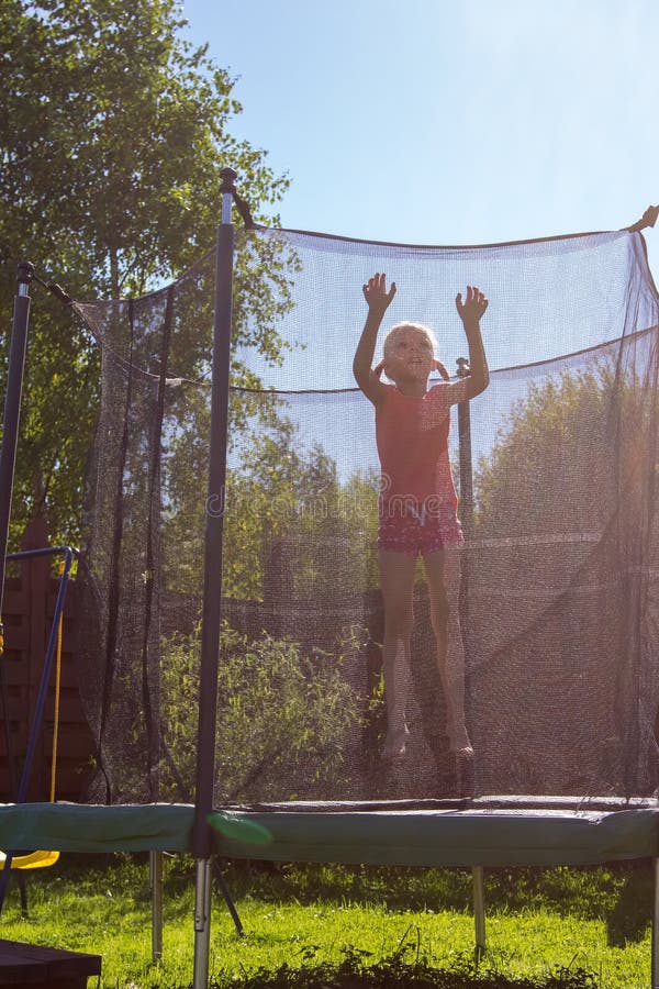 Girl Jumping on a Trampoline Behind Protective Net Stock Image - Image ...
