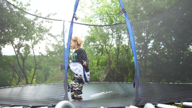 Girl Jumping on a Trampoline that Stands in the Park among the Trees ...