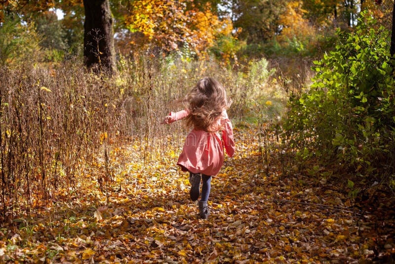 A Girl with Long Hair Runs Along a Path in the Park in the Fall Stock ...
