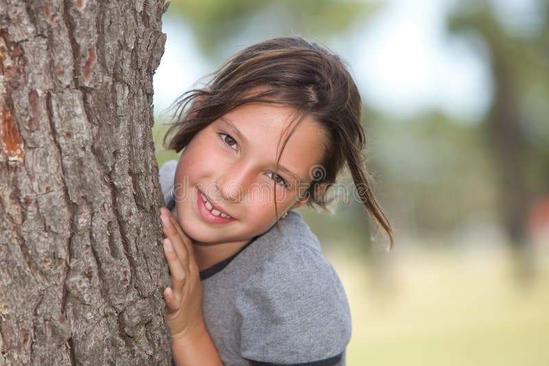 Girl Looking from Behind a Tree Stock Photo - Image of play, childhood ...