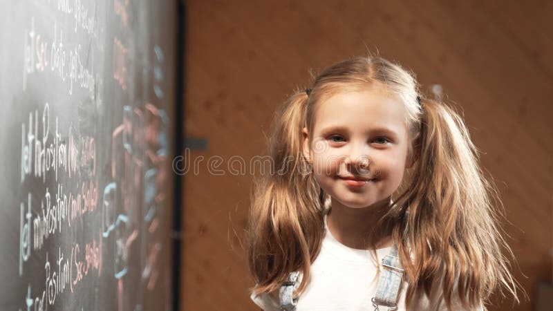 Girl Looking and Smiling at Camera while Standing at Blackboard ...