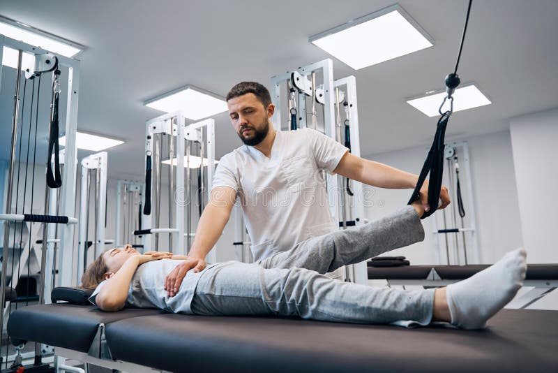 Girl Lying on Physical Therapy Bed, Doing Exersises on Elastic Strength ...