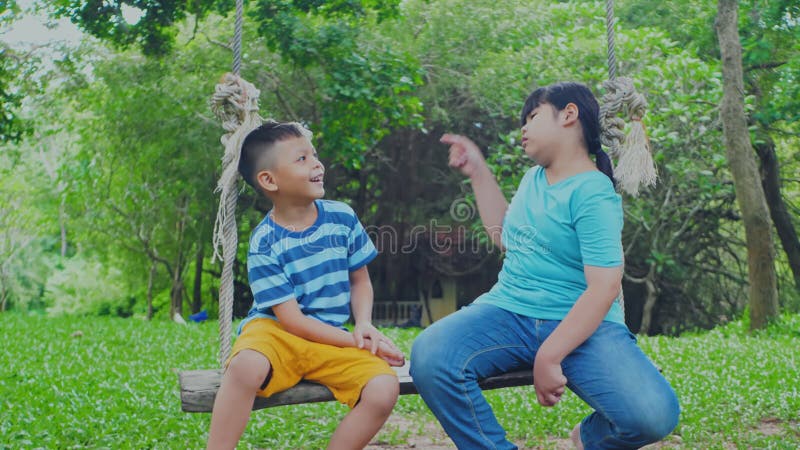 A Girl and a Man Reading a Book on a Swing in the Garden Stock Video ...