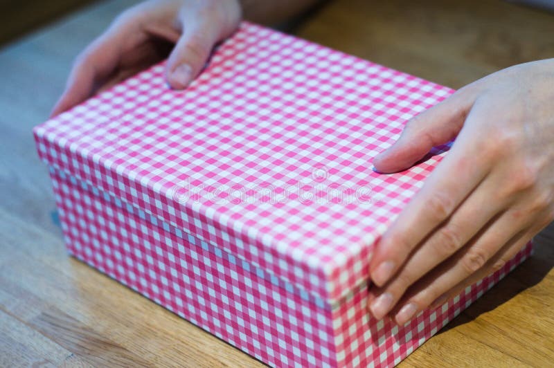 A Girl Opening a Checkered Pink Box on a Wooden Table Stock Photo ...