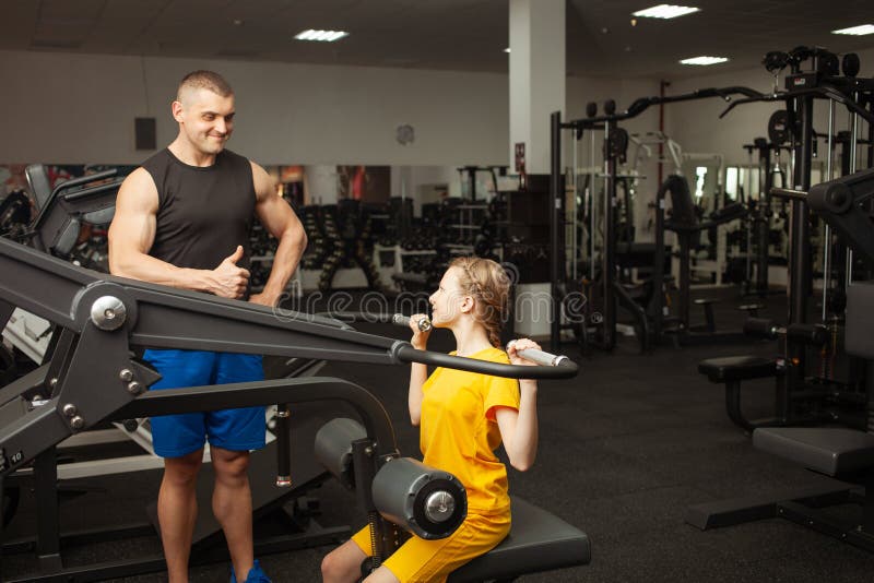 Girl Performs an Exercise on Simulator, Coach Teaches Stock Photo ...