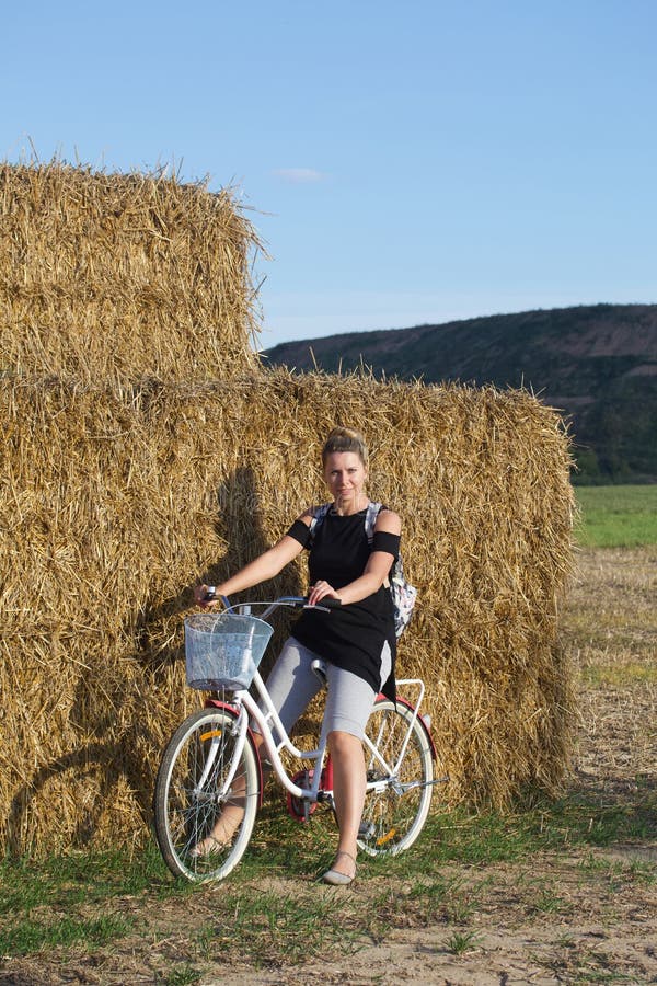 Girl Posing Near a Stack of Straw. Sits on a Bike Stock Photo - Image ...