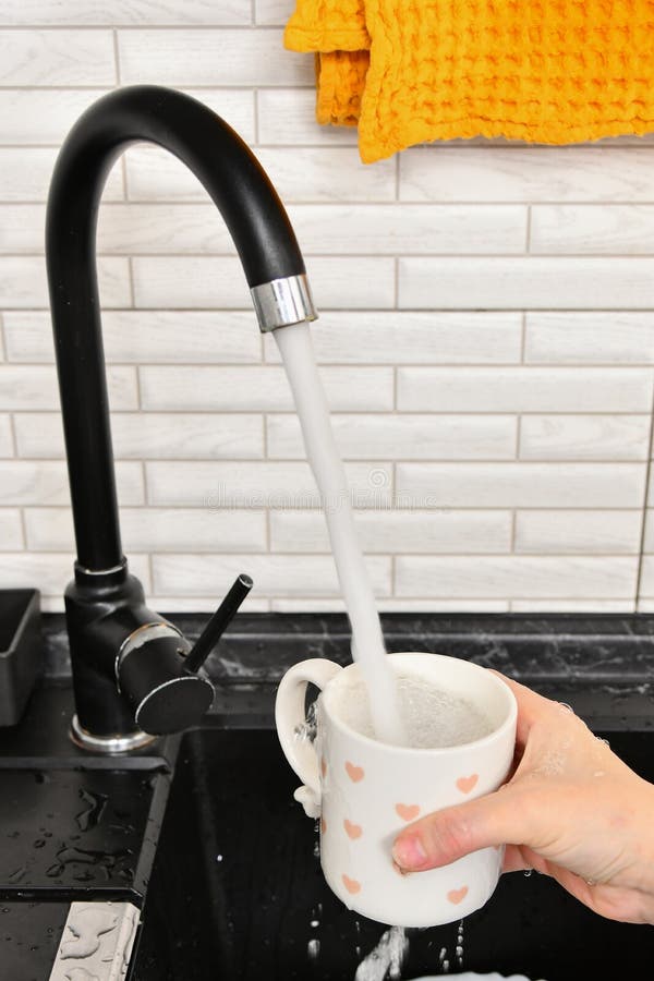 The Girl Pours Water from the Tap in the Kitchen into a Drinking Cup ...