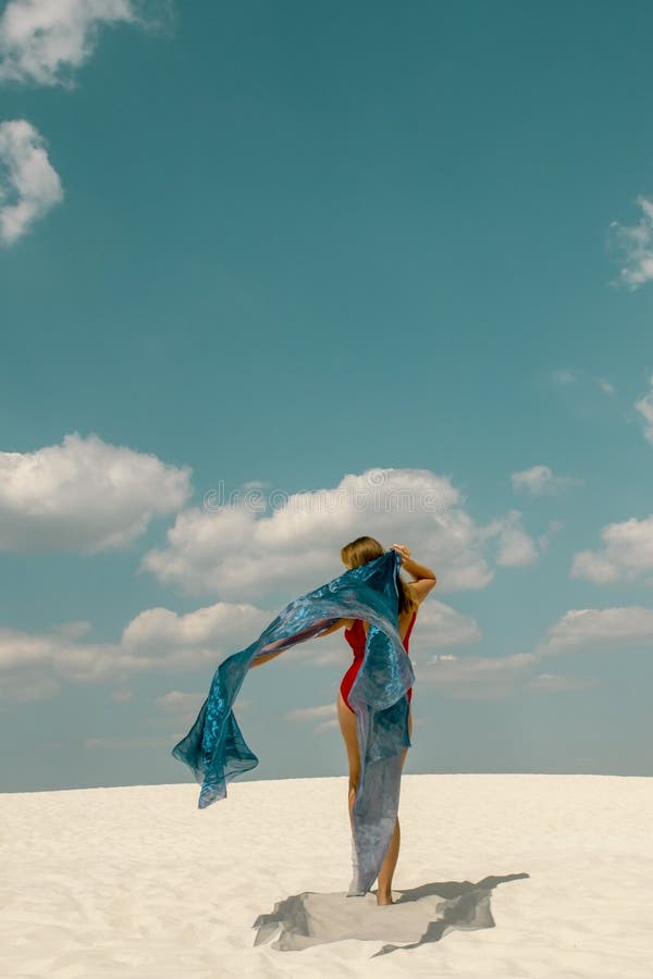 Girl in a Red Swimsuit on the Beach. Blue Cape Fluttering in the Wind ...