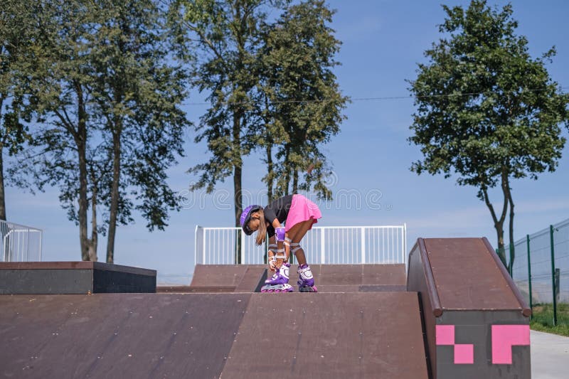 A Girl on Roller Skates Stands at the Top of the Skate Park Ramp Stock ...