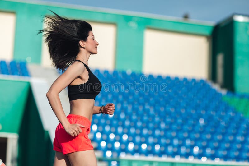 Side View Athletic Woman On Running Track Getting Ready To Start Run