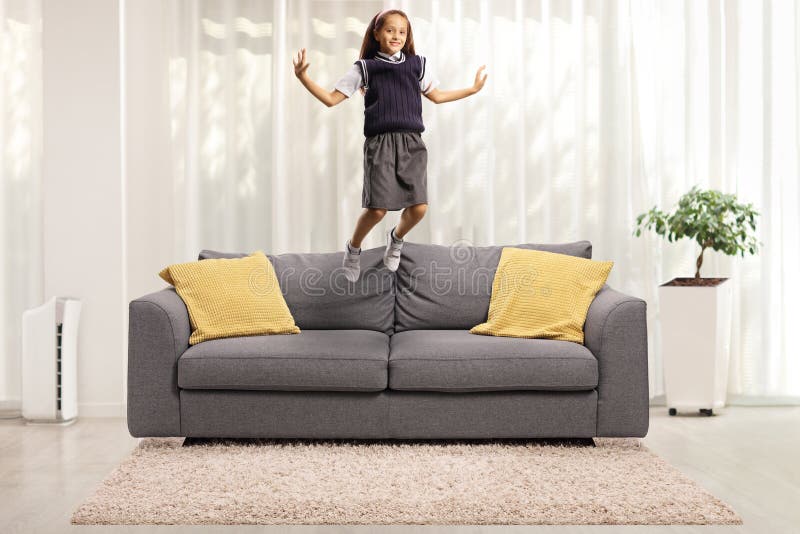 Girl in a School Uniform Jumping on Sofa at Home Stock Image - Image of ...