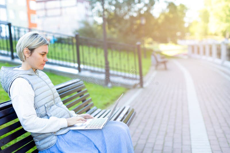A Girl Sits on a Park Bench with a Laptop and Works Stock Image - Image ...