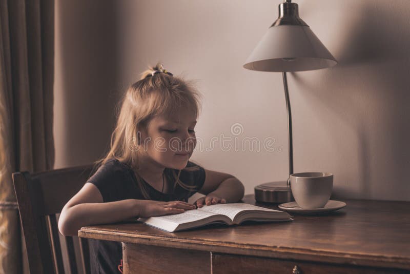 A Girl Sits at a Table Reading a Book Stock Photo - Image of isolated ...