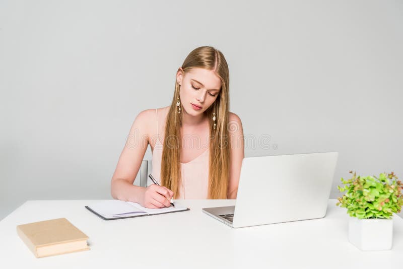 Girl Sitting at Computer Desk and Writing in Notebook on Grey Stock ...