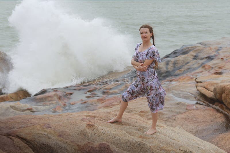 The Girl is Sitting on a Large Rock, on Which the Waves are Breaking ...