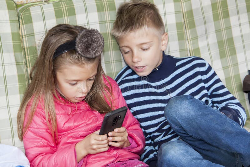 Girl Is Sitting On Swing And Playing Mobile Games On Smart Phone Boy Sits Next To Her And 4589